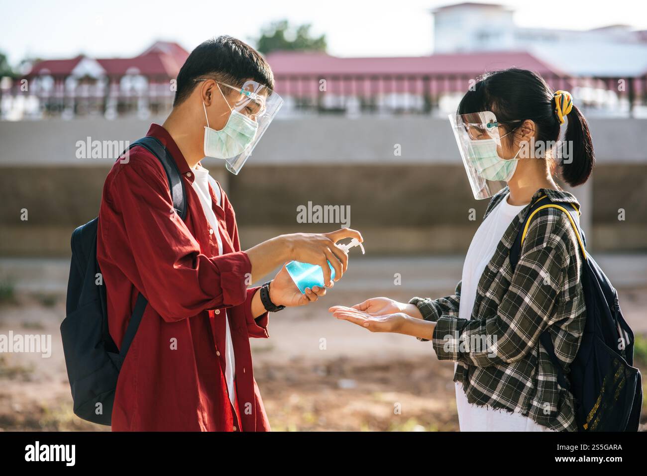 Male and female students wear masks and squeeze the gel to wash their ...