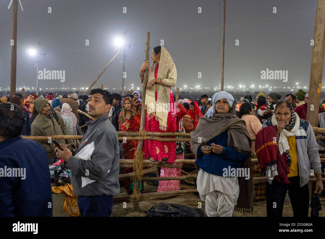 A woman stands on the horizontal bamboo bar of a barrier as she waits ...