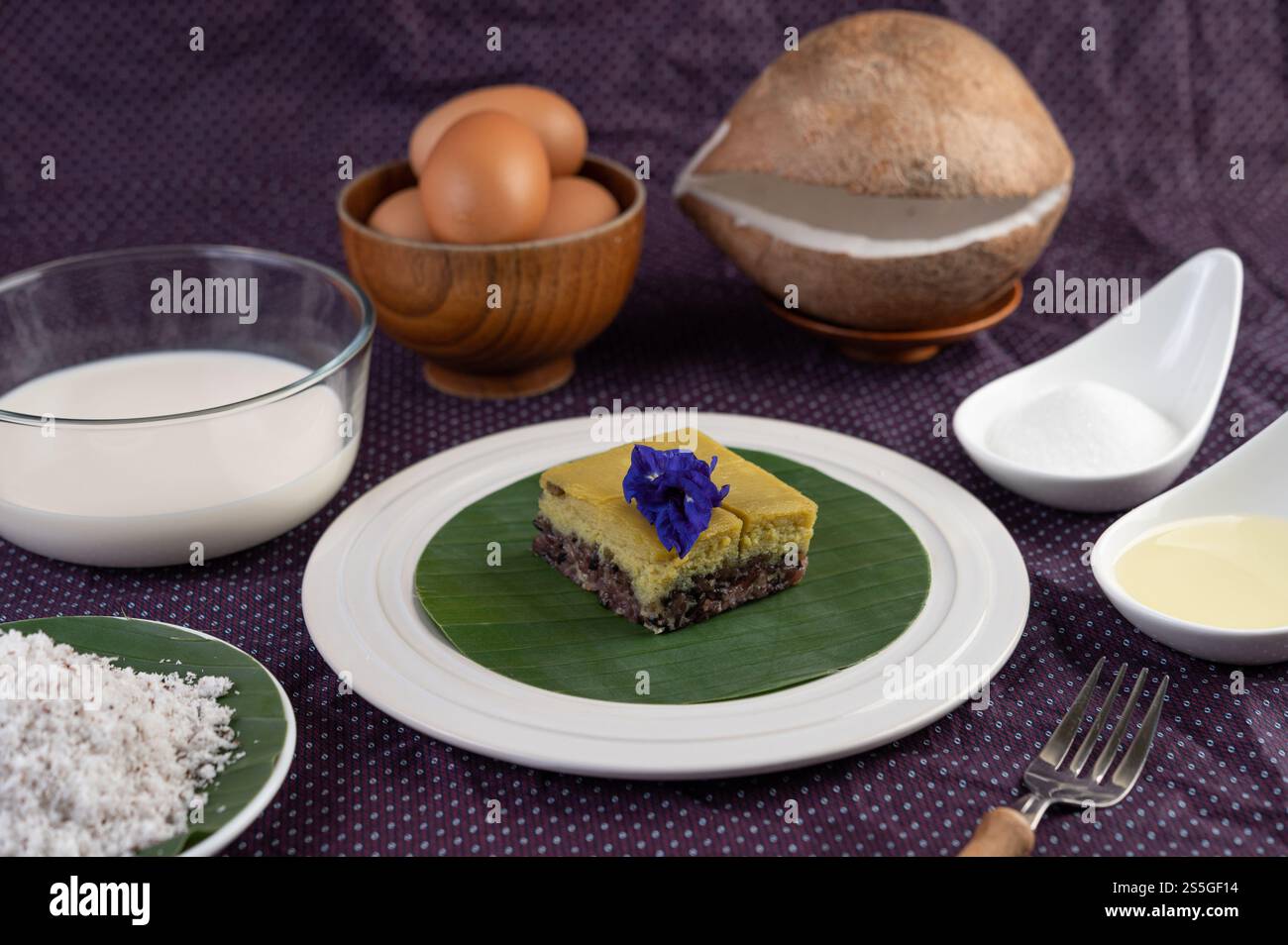 Black sticky rice and custard on a banana leaf in a white plate with ...