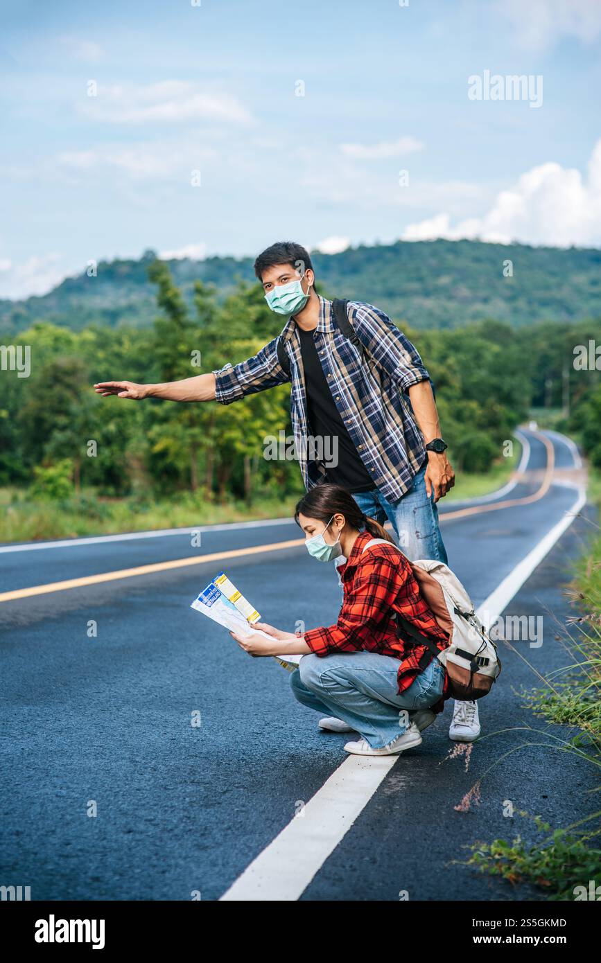 Female tourists sit and look at the map, male tourists pretending to ...