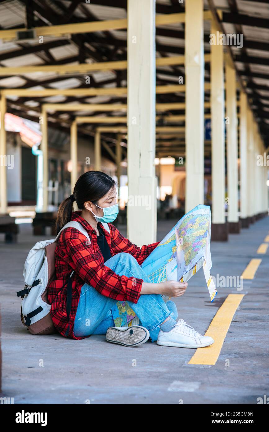 Female tourists sit and look at the map on the footpath beside the ...