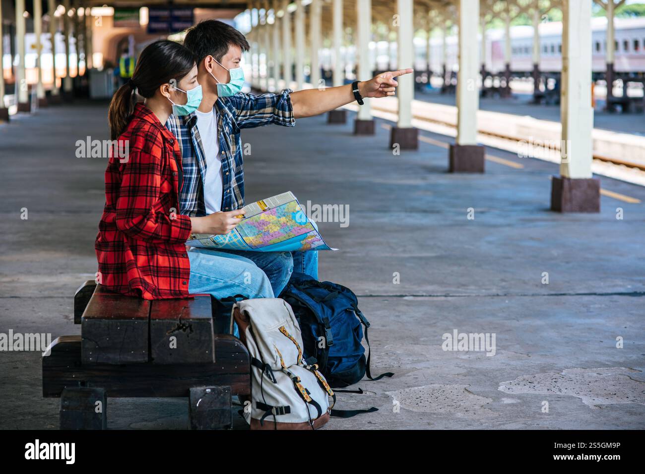Male and female tourists look at the map beside the railway Stock Photo ...