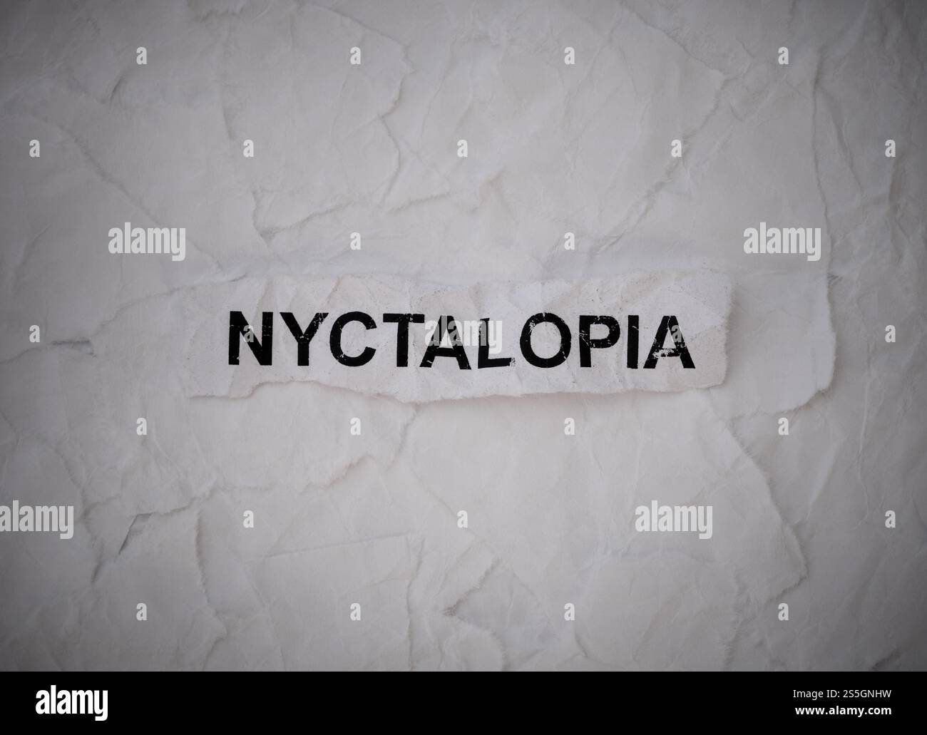 Crumpled piece of paper with word Nyctalopia on torn white paper pieces ...