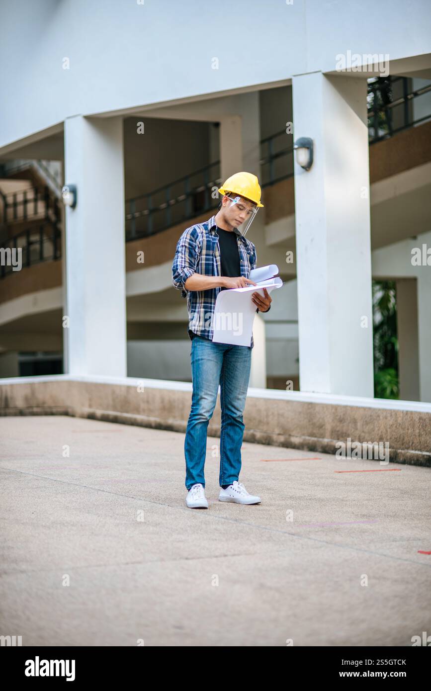 Architects hold the building plan and check the work Stock Photo - Alamy