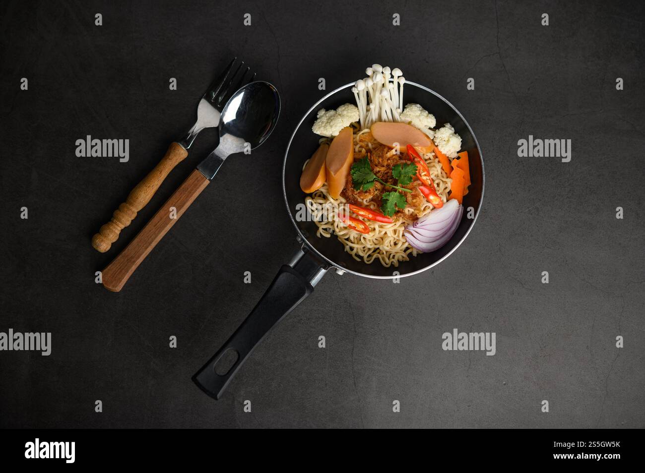 Still life with the noodles in a frying pan, fork, and spoon on the ...