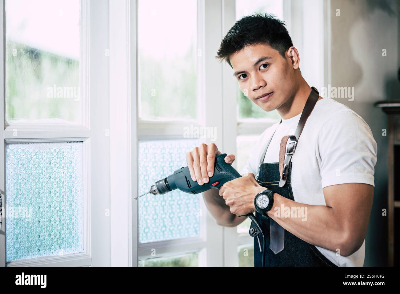 The carpenter holds the drill and drills the window. Selective focus ...