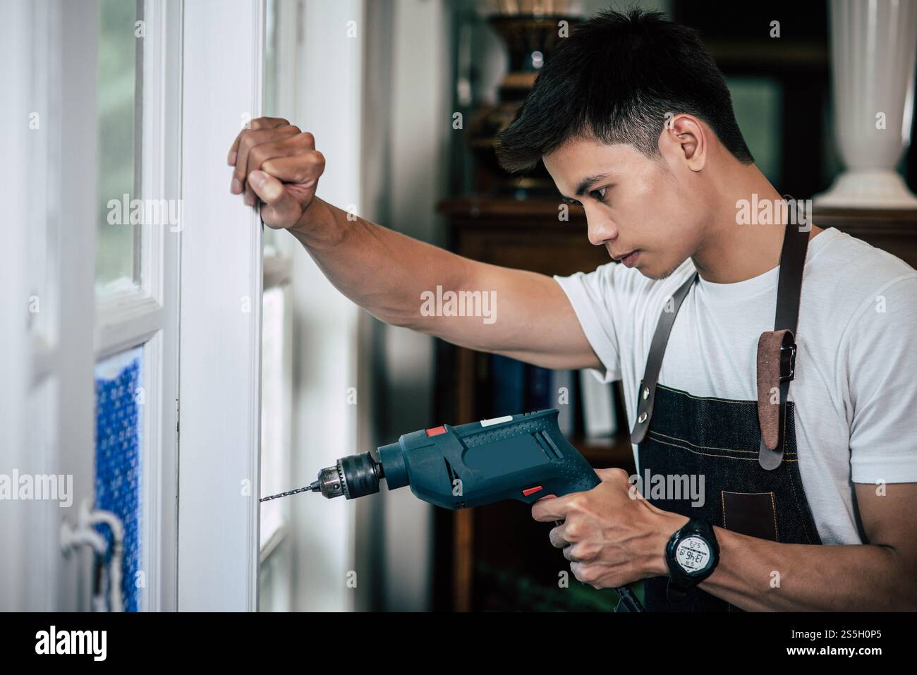 The carpenter holds the drill and drills the window. Selective focus ...