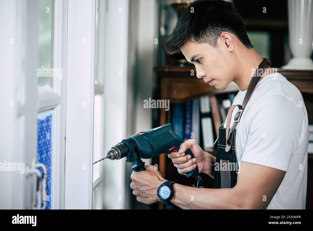 The carpenter holds the drill and drills the window. Selective focus ...