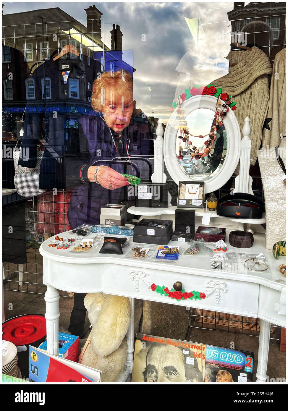 Elderly lady seen through the shopfront window of a charity store Stock ...