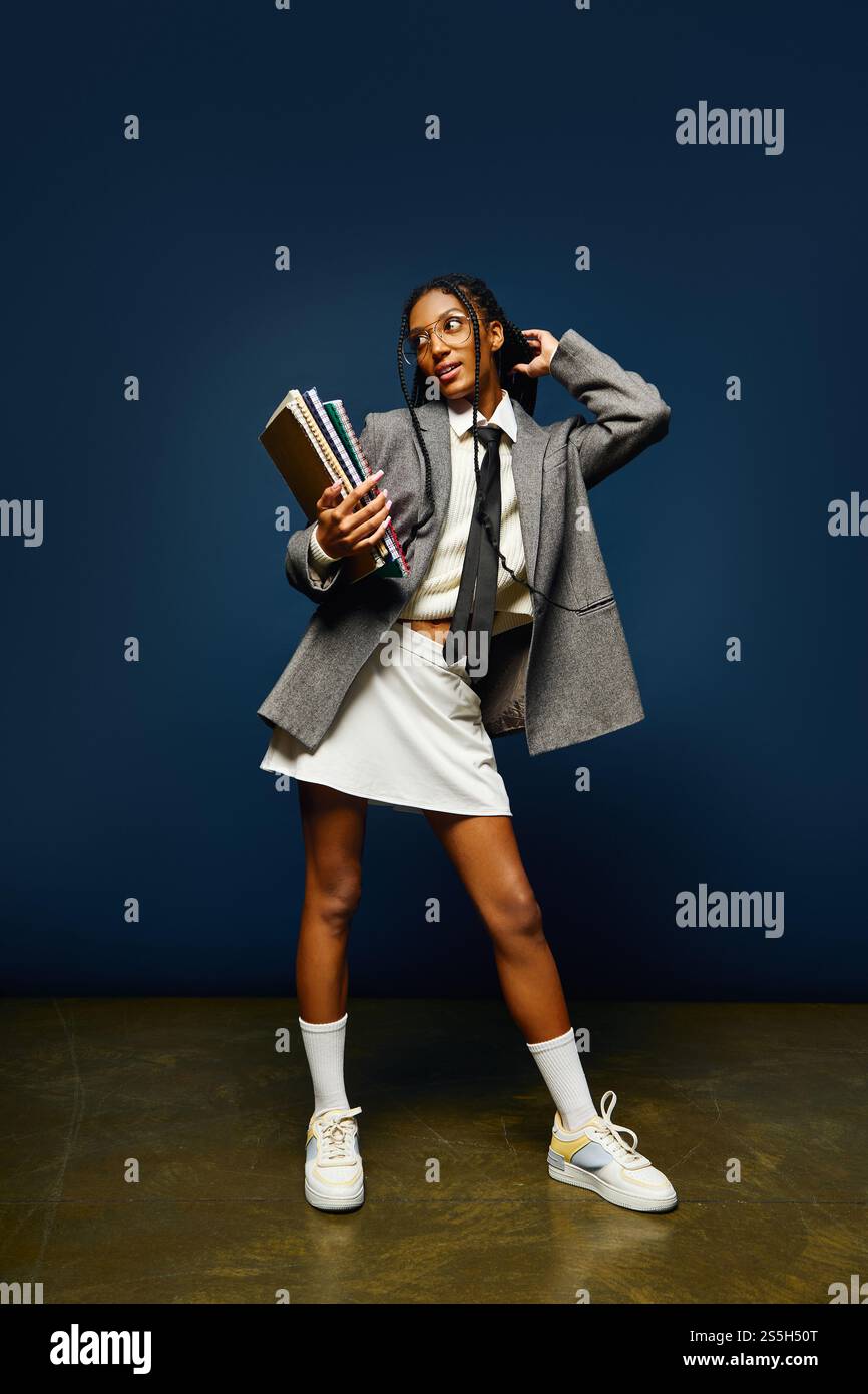A confident young woman poses gracefully with books in hand, showcasing ...