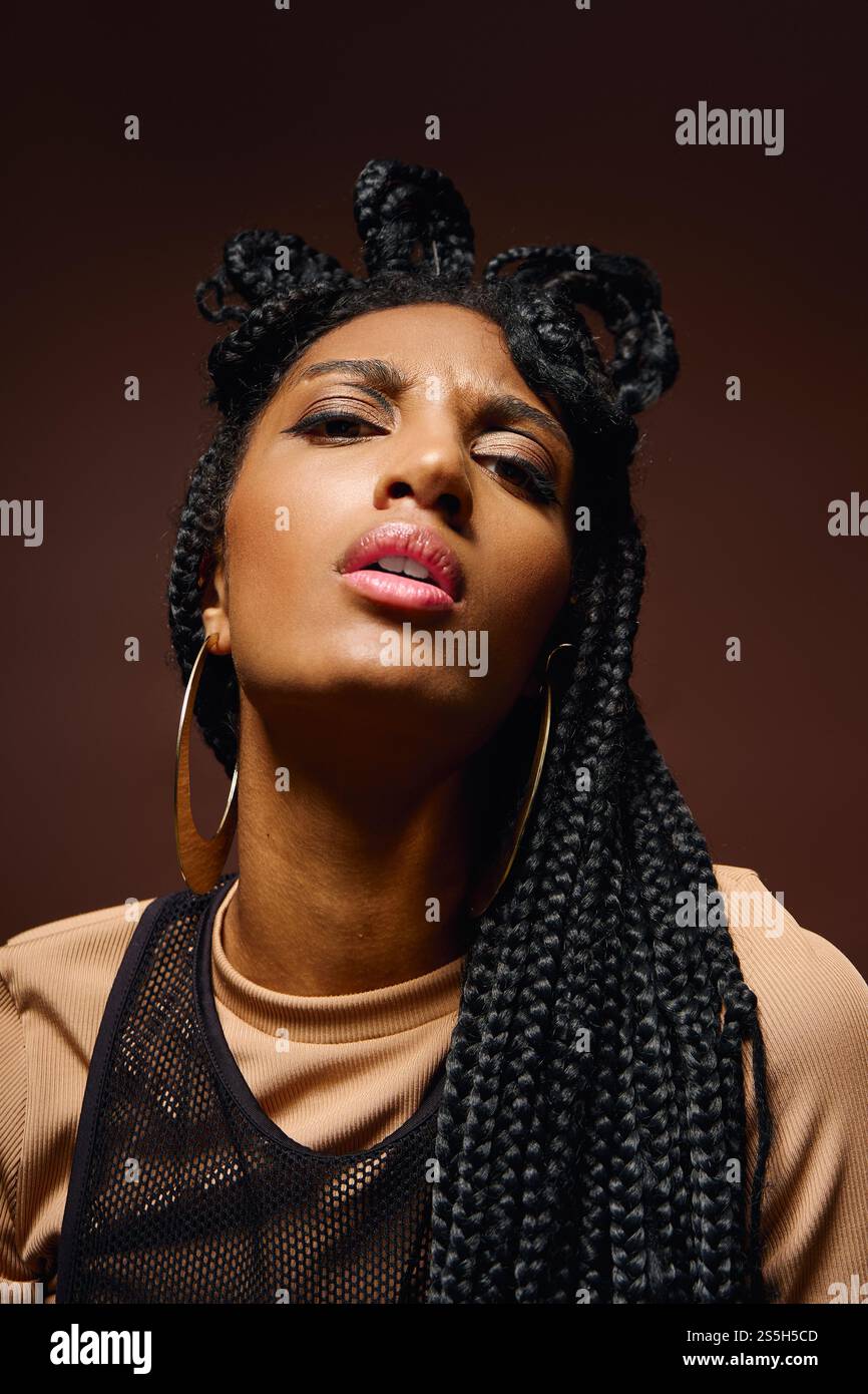 A confident young woman shows off her intricate braids against a dark ...