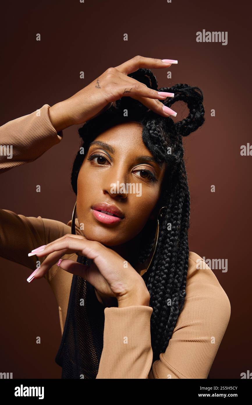 A young woman poses gracefully, hands framing her face and showcasing ...
