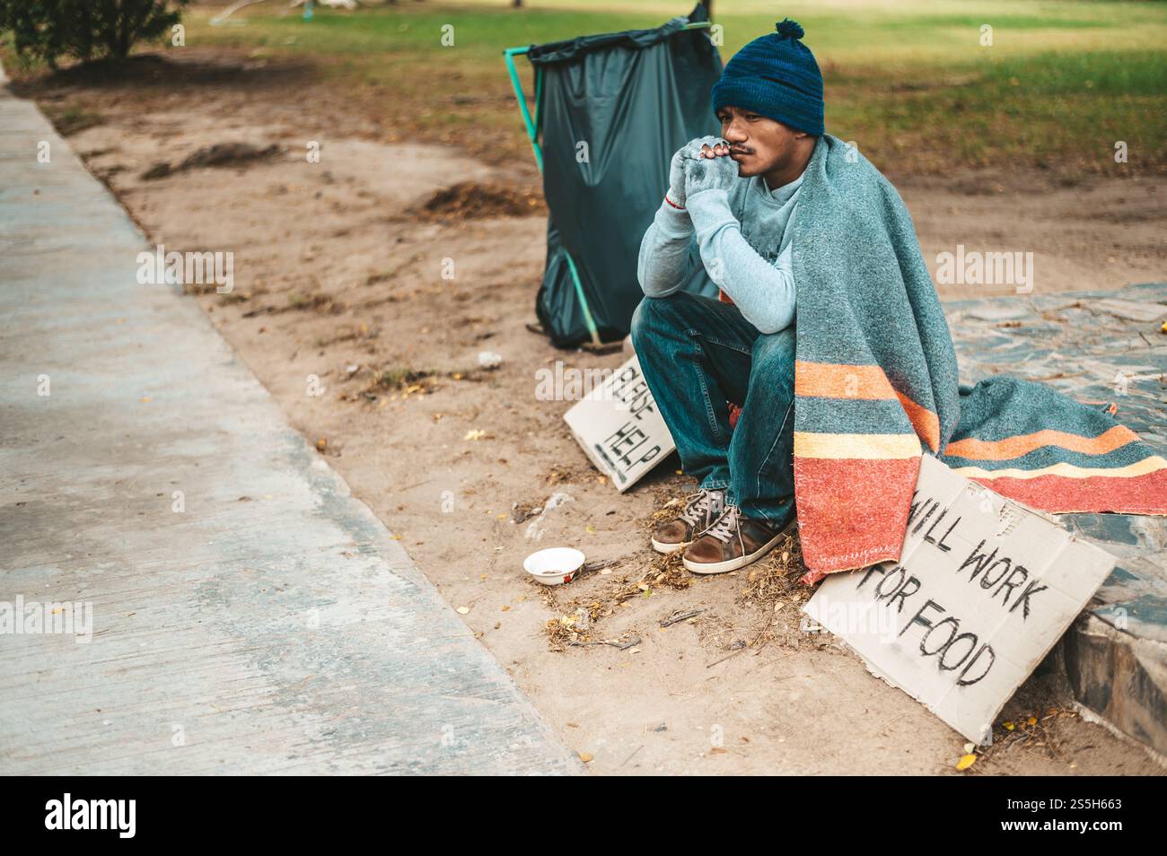 a man sitting beggars with homeless please help message. Selective ...