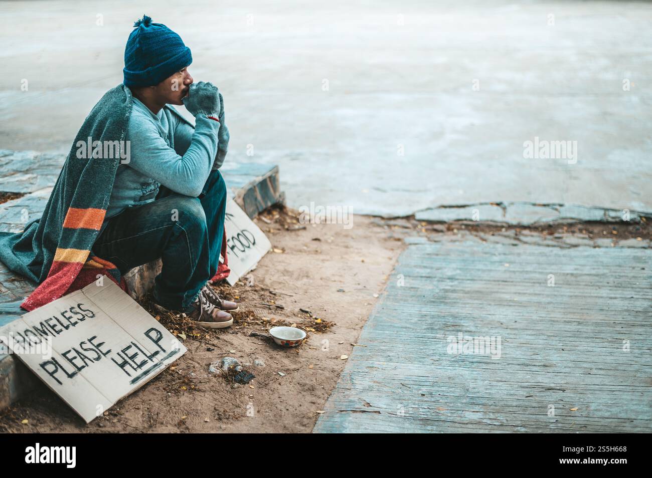 a man sitting beggars with homeless please help message. Selective ...
