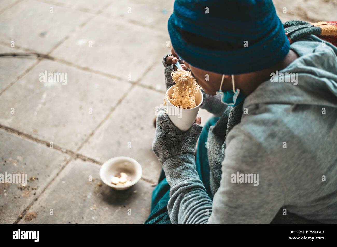The beggars sat wrapped in cloths and eating noodles Stock Photo - Alamy