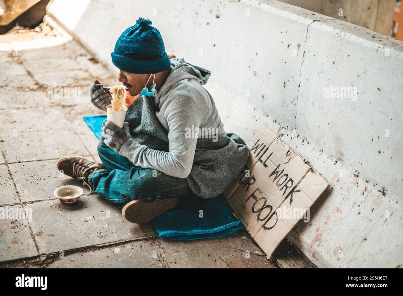 The beggars sat wrapped in cloths and eating noodles Stock Photo - Alamy