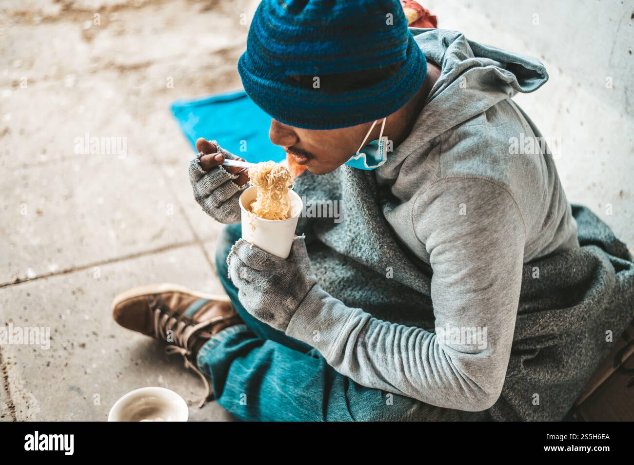 The beggars sat wrapped in cloths and eating noodles Stock Photo - Alamy