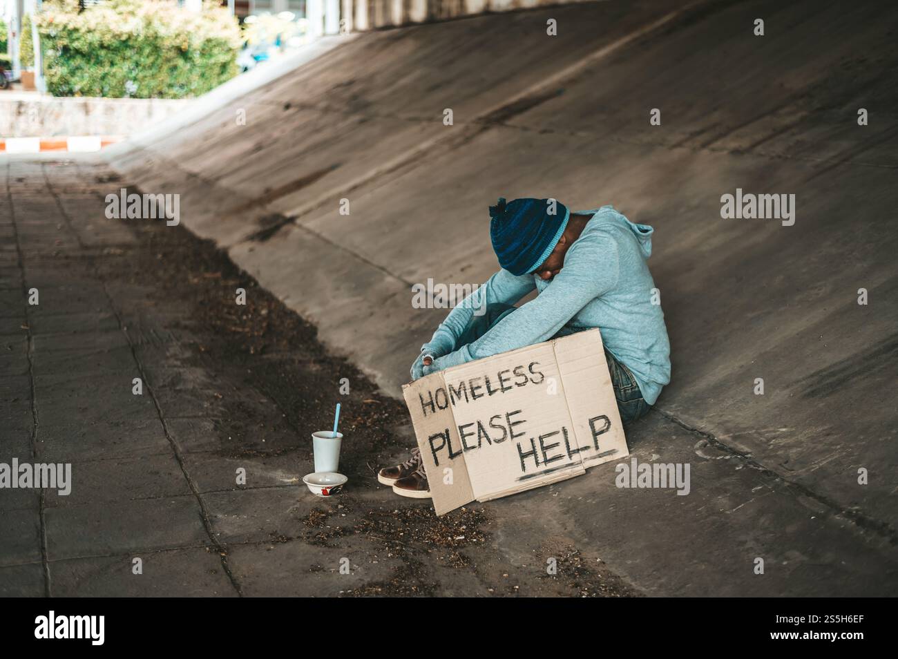 The beggars sit under the bridge with a homeless message. Please help ...