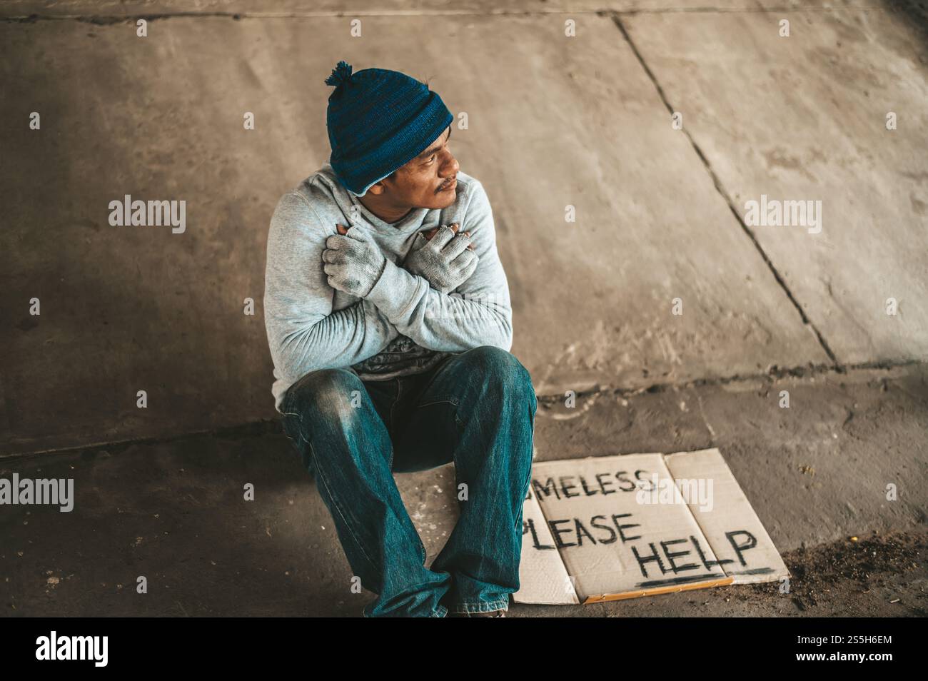 The beggars sit under the bridge with a homeless message. Please help ...