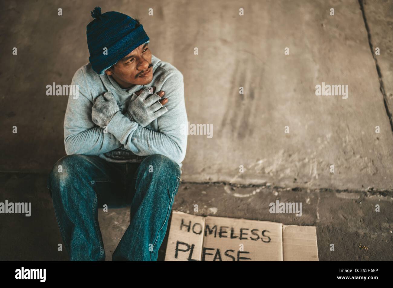 The beggars sit under the bridge with a homeless message. Please help ...