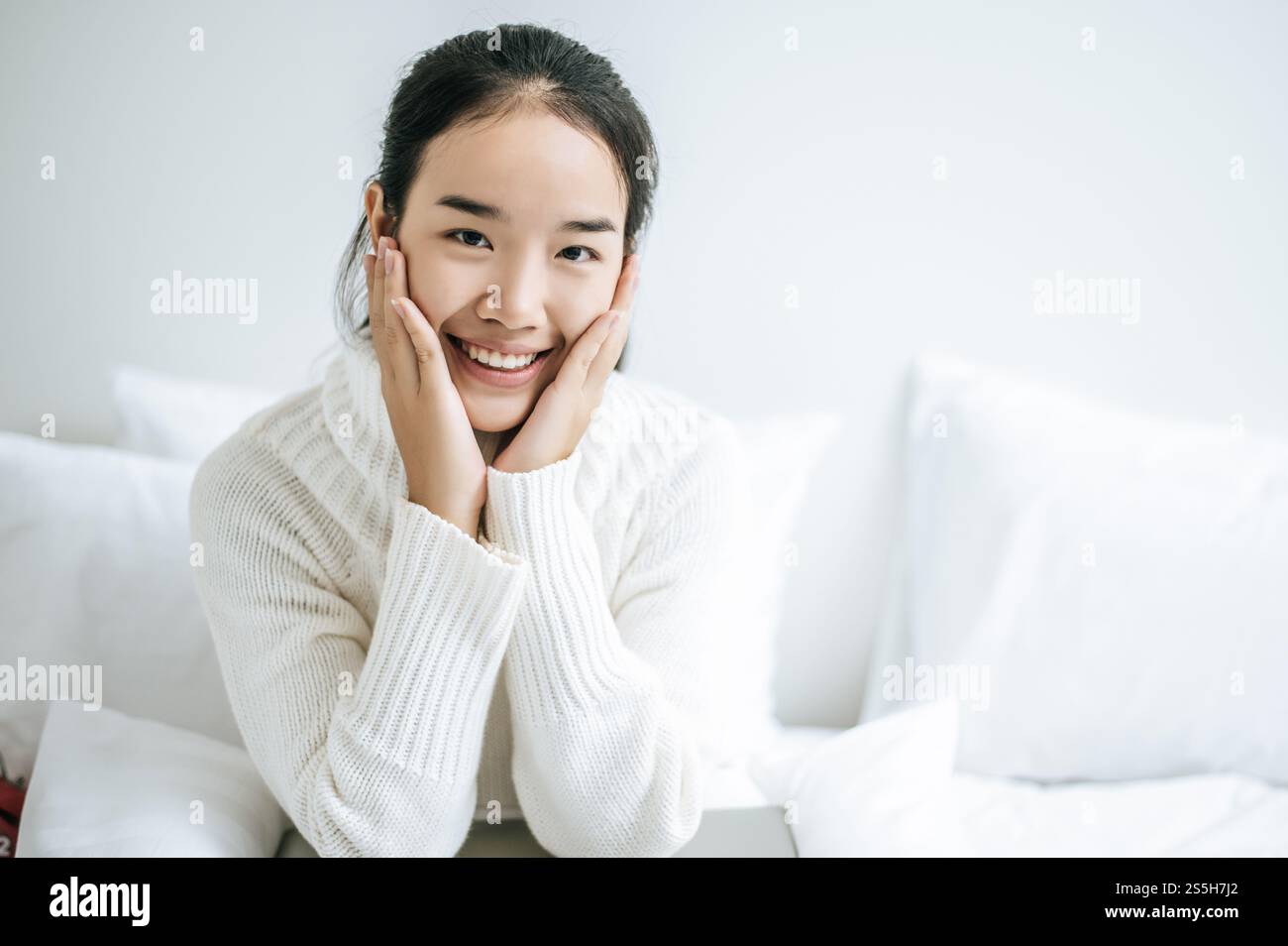 The woman sat on the bed, held the cheek, and smiled happily Stock ...