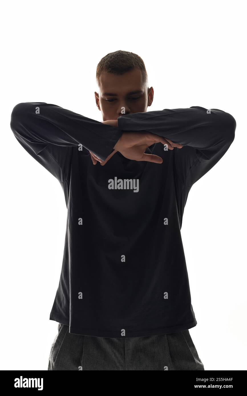 A young man striking an expressive pose with arms crossed, showcasing ...