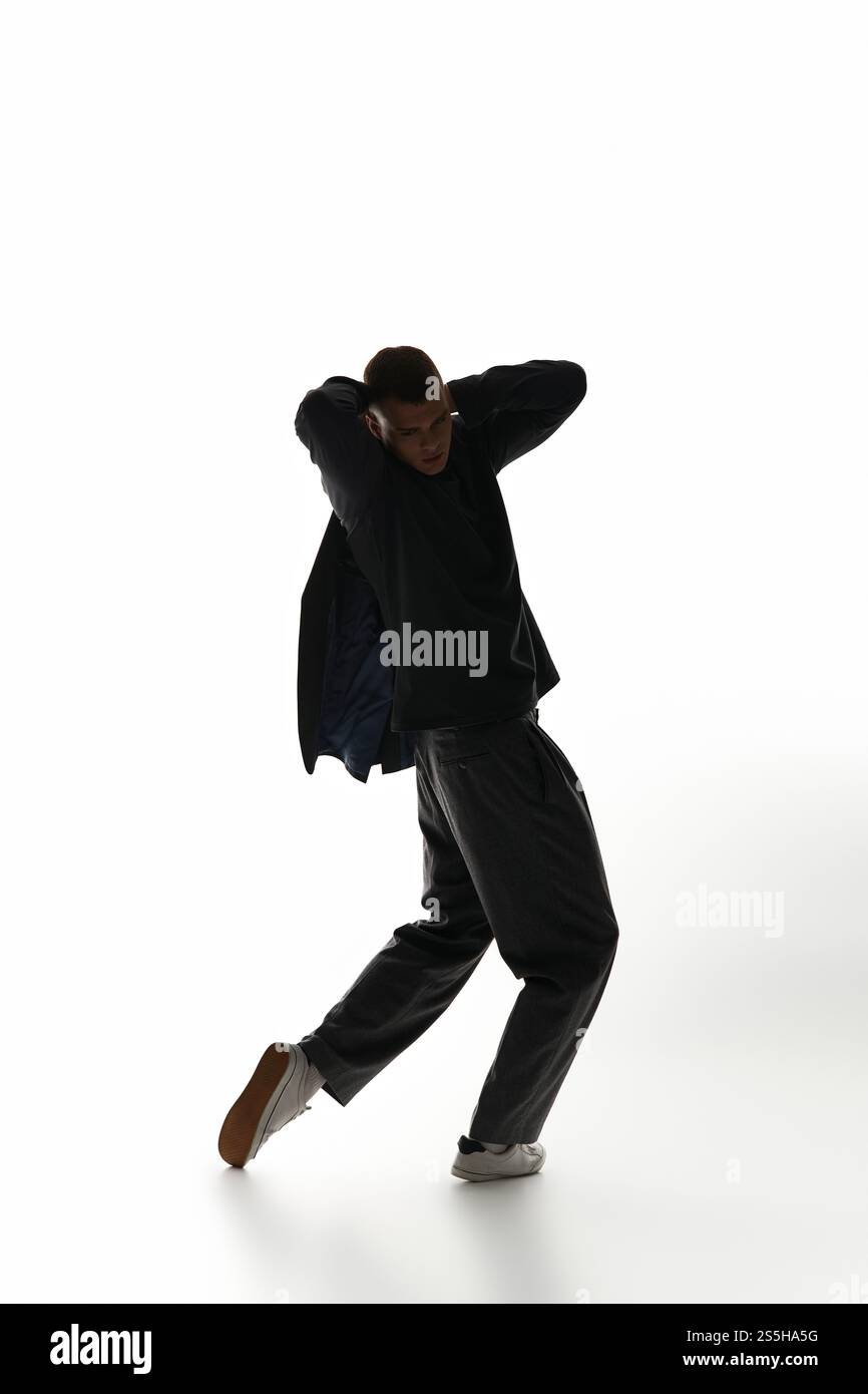 A handsome young man strikes a unique pose, showcasing fashion in a ...