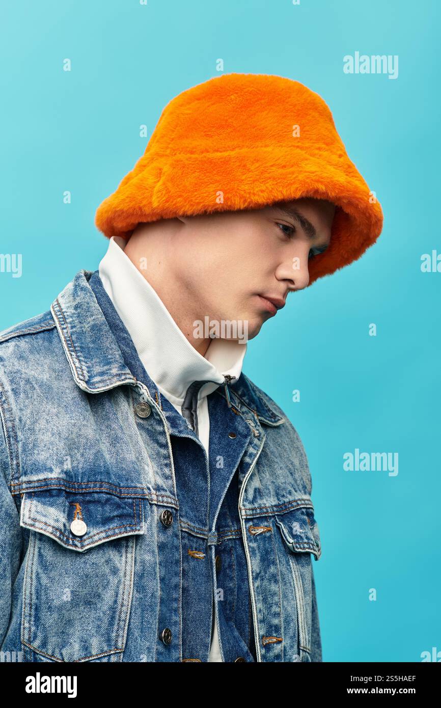 A young man shows off modern style in a denim jacket and orange bucket ...