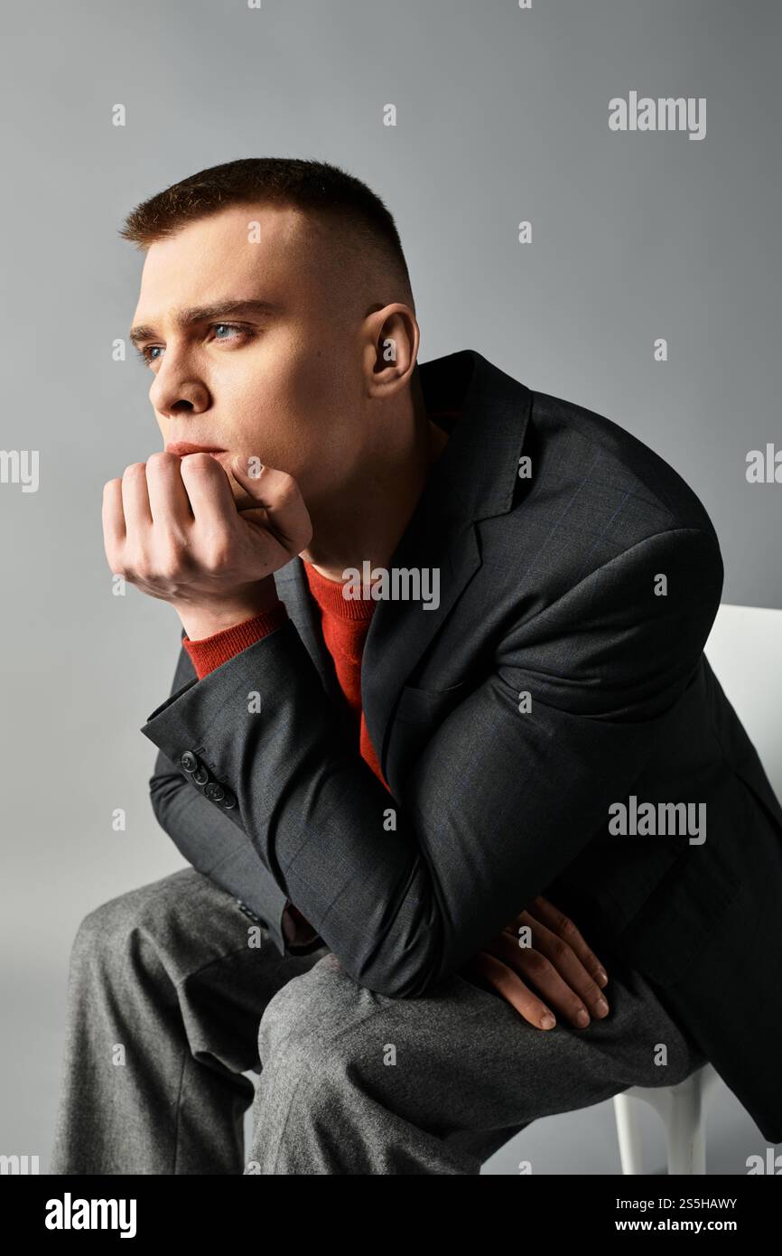 A handsome young man rests his chin on his hand, deep in thought ...