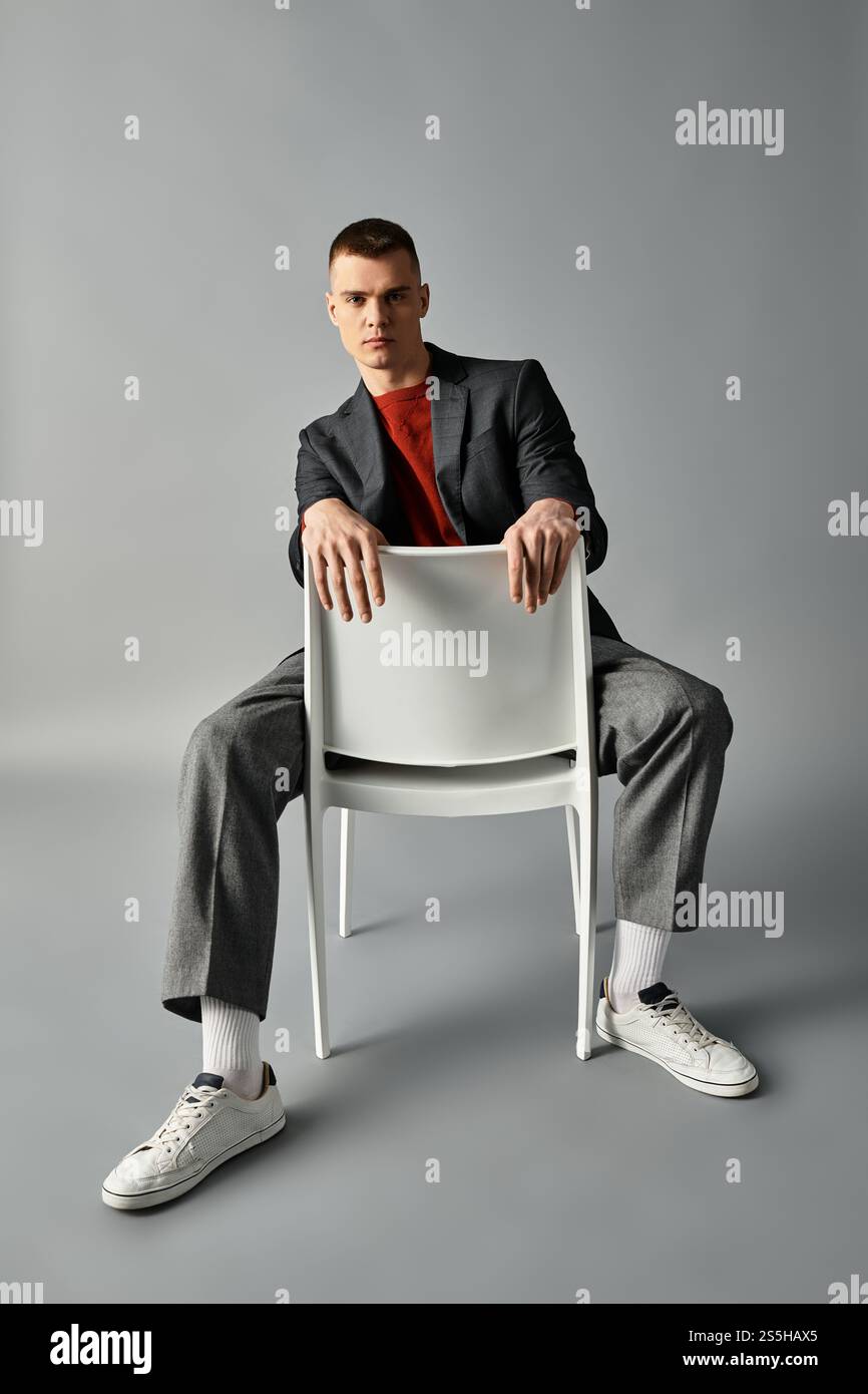 A young man wearing a blazer and sneakers engages the viewer with a ...