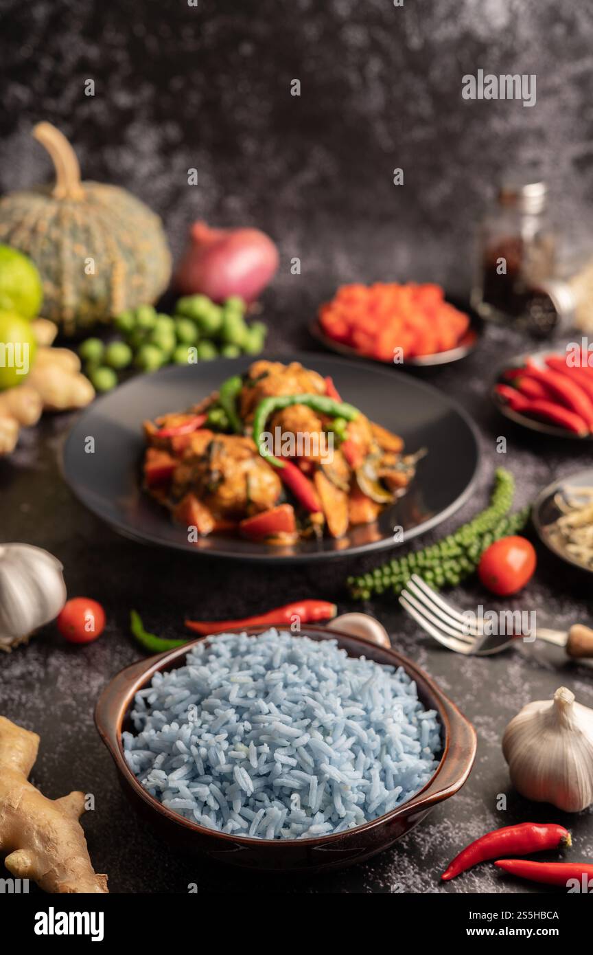 Butterfly Pea flower rice in a brown cup with spices on black cement ...