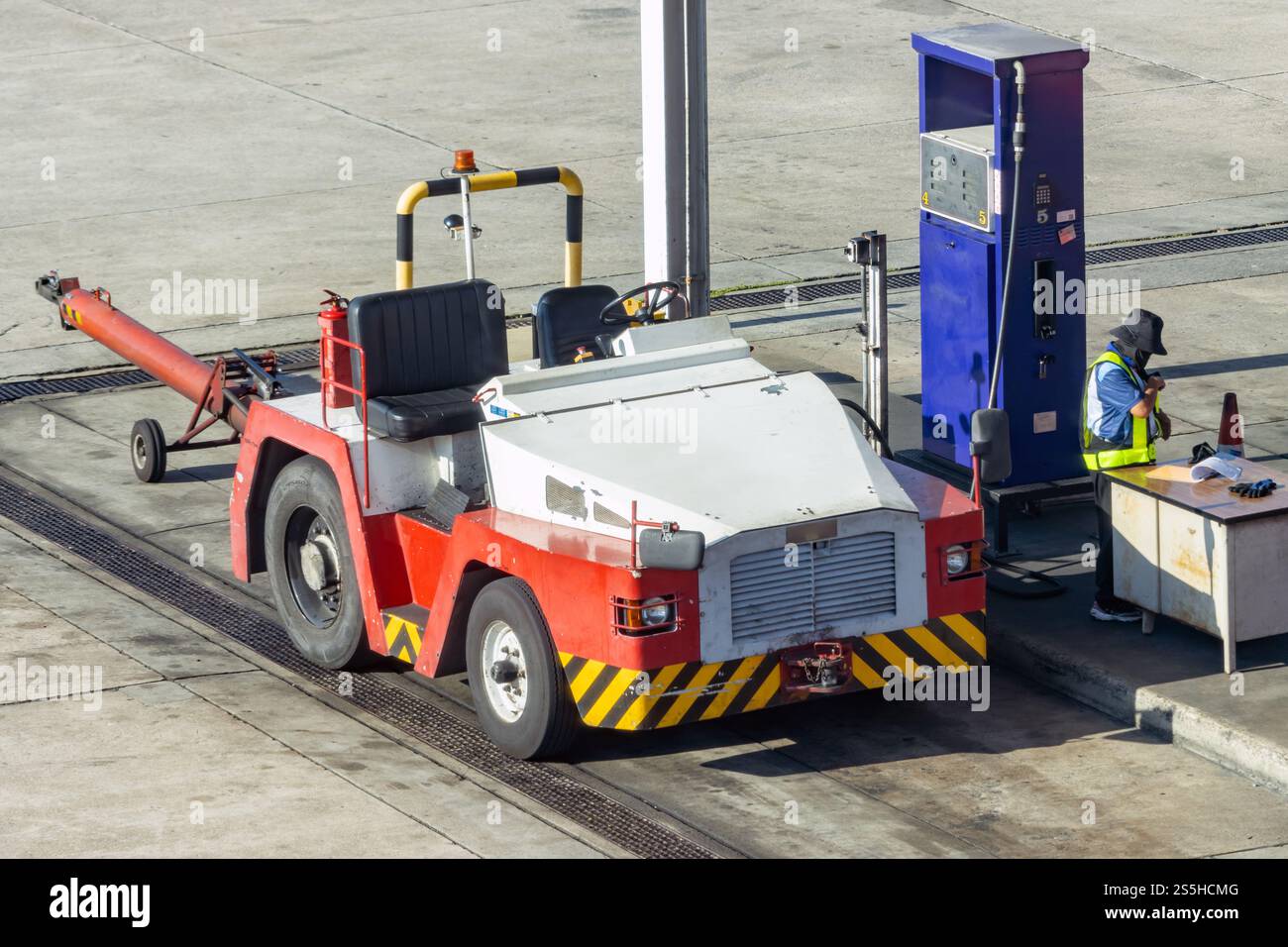 A tractor for pulling luggage carts pumps fuel at a gas station at the ...