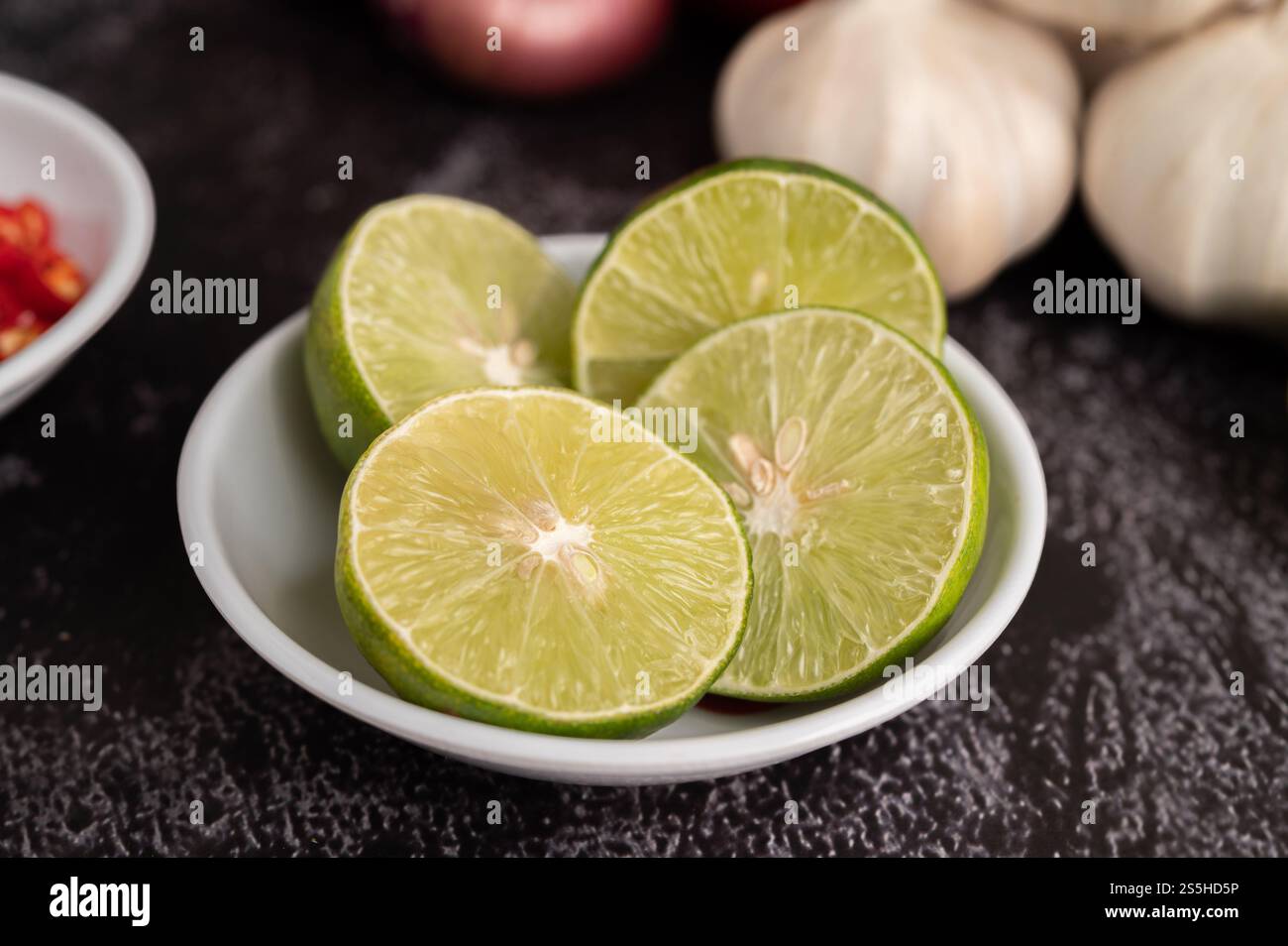 Half cut lime in a white cup on black cement. Selective focus Stock ...
