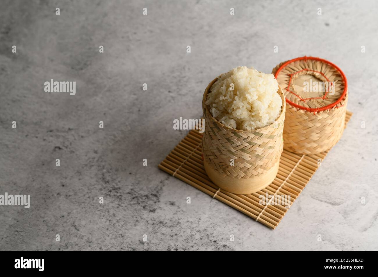 Thai sticky rice in a woven bamboo basket on a wooden panel. Selective ...