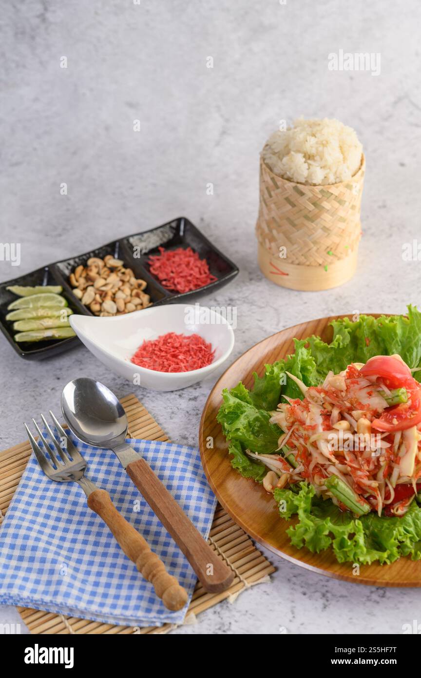 Thai papaya salad in a wooden plate with Sticky rice, Spoon, and fork ...