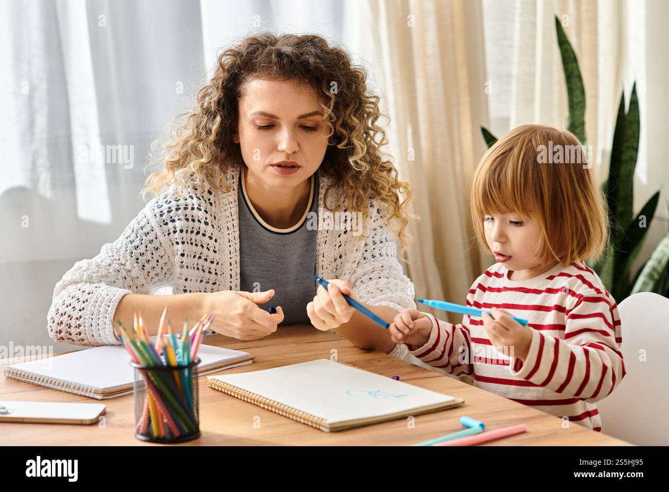 A mother and her daughter engage in a fun drawing session, bonding ...
