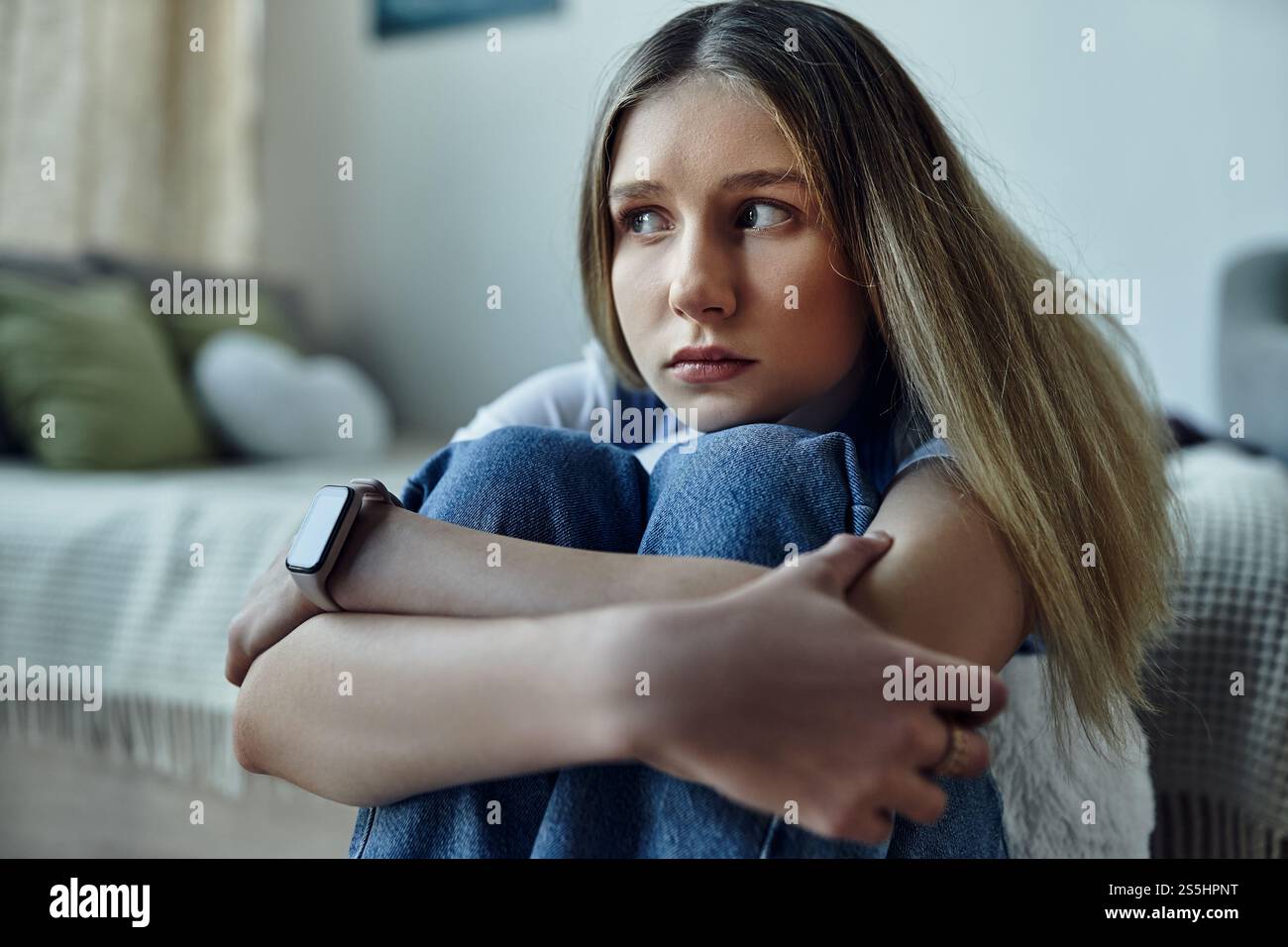 A pretty girl sits curled up in her room, lost in thought, surrounded ...