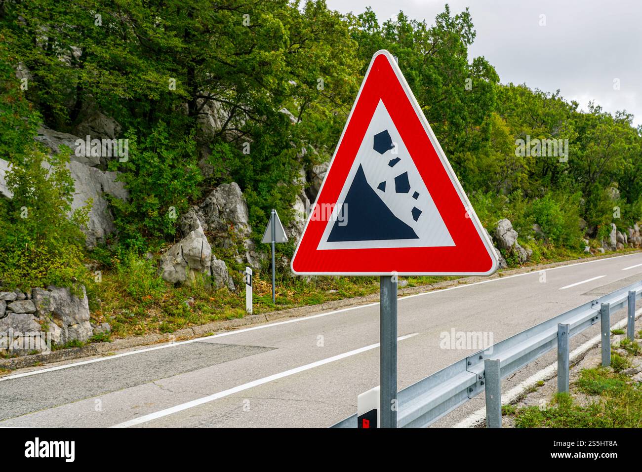 rockfall warning sign on the background of the crumbling hillside ...