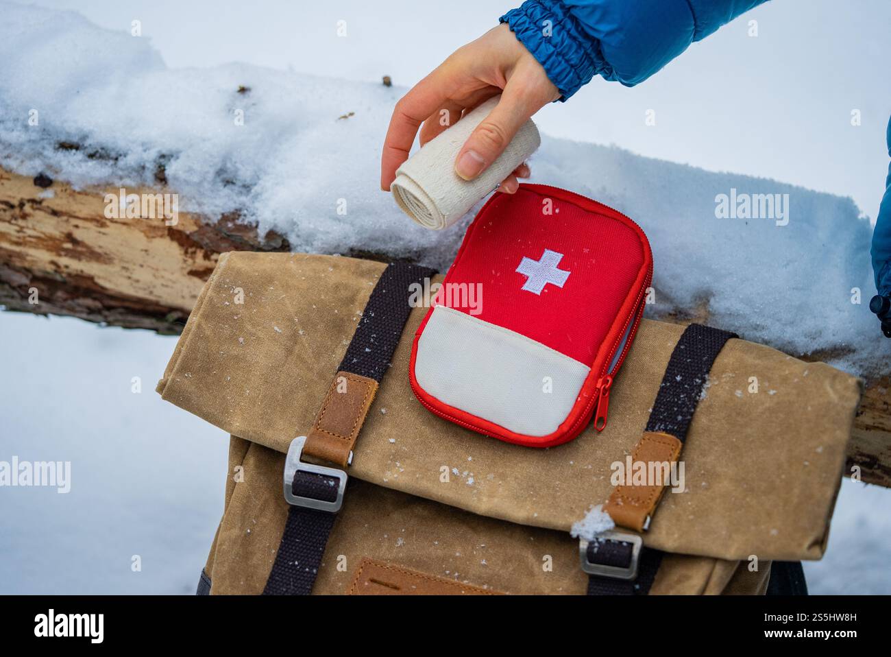 Hiker retrieving a bandage from a first aid kit positioned on a ...