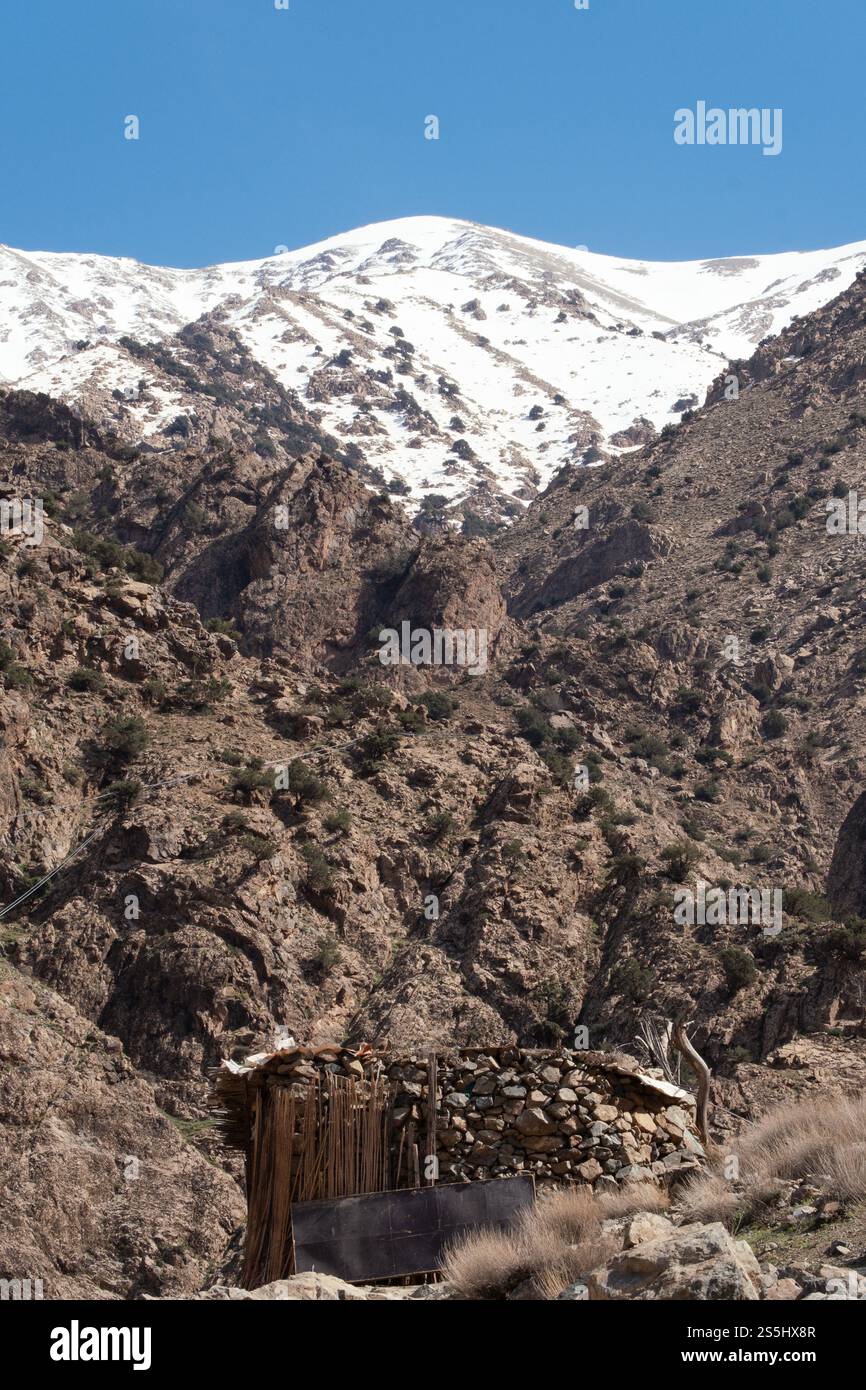 Peak of a snow mountain above the dirt mountains of the Ourika Valley ...