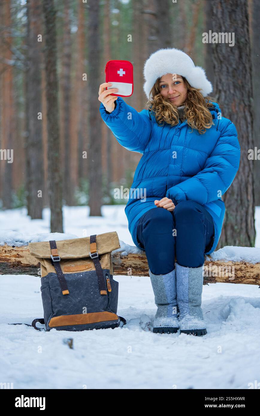 Female hiker sitting on a fallen tree trunk in snowy winter forest ...