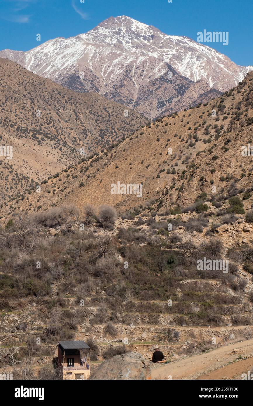 Peak of a snow mountain above the dirt mountains of the Ourika Valley ...