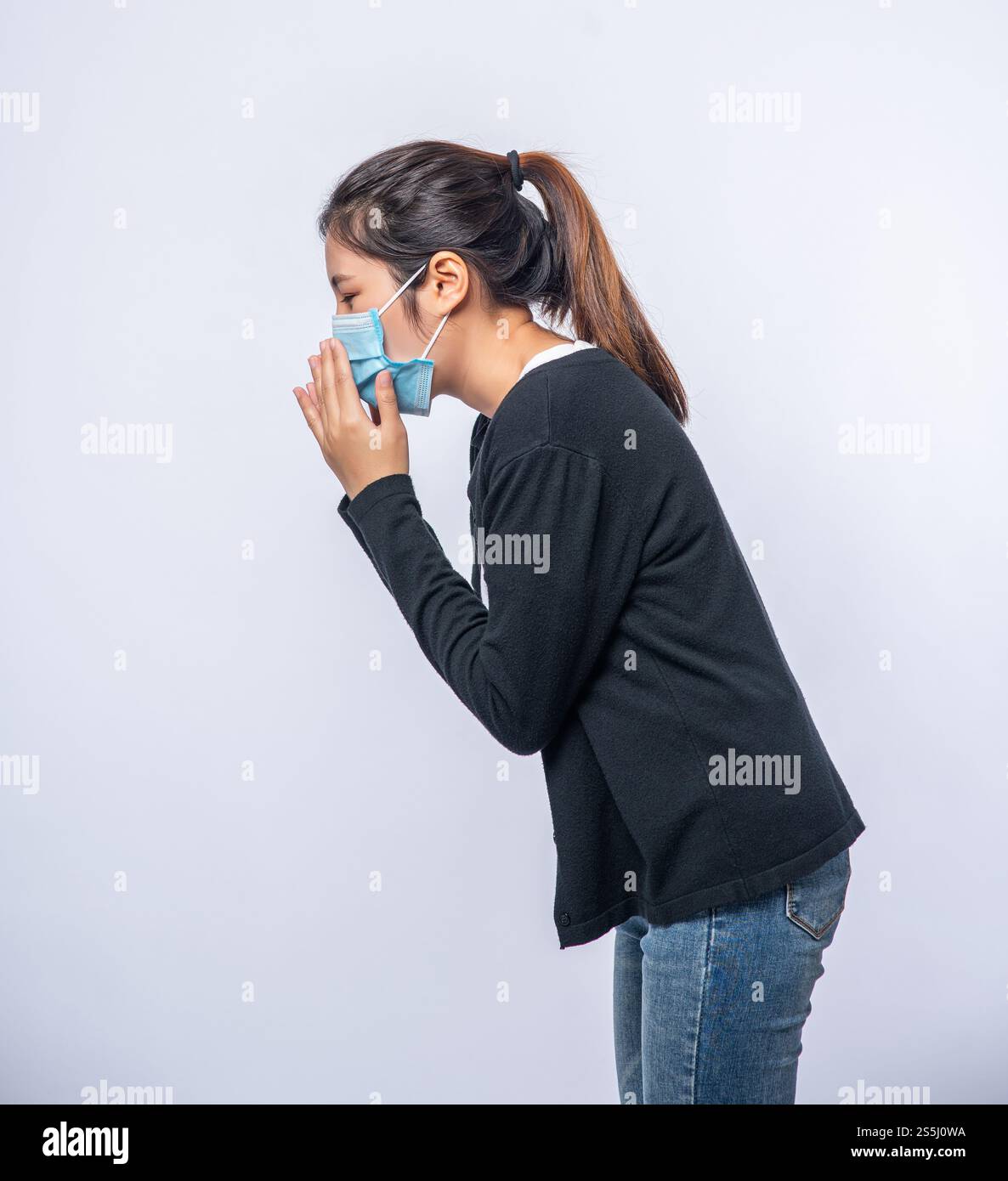 A woman coughing and covering her mouth with her hand Stock Photo - Alamy