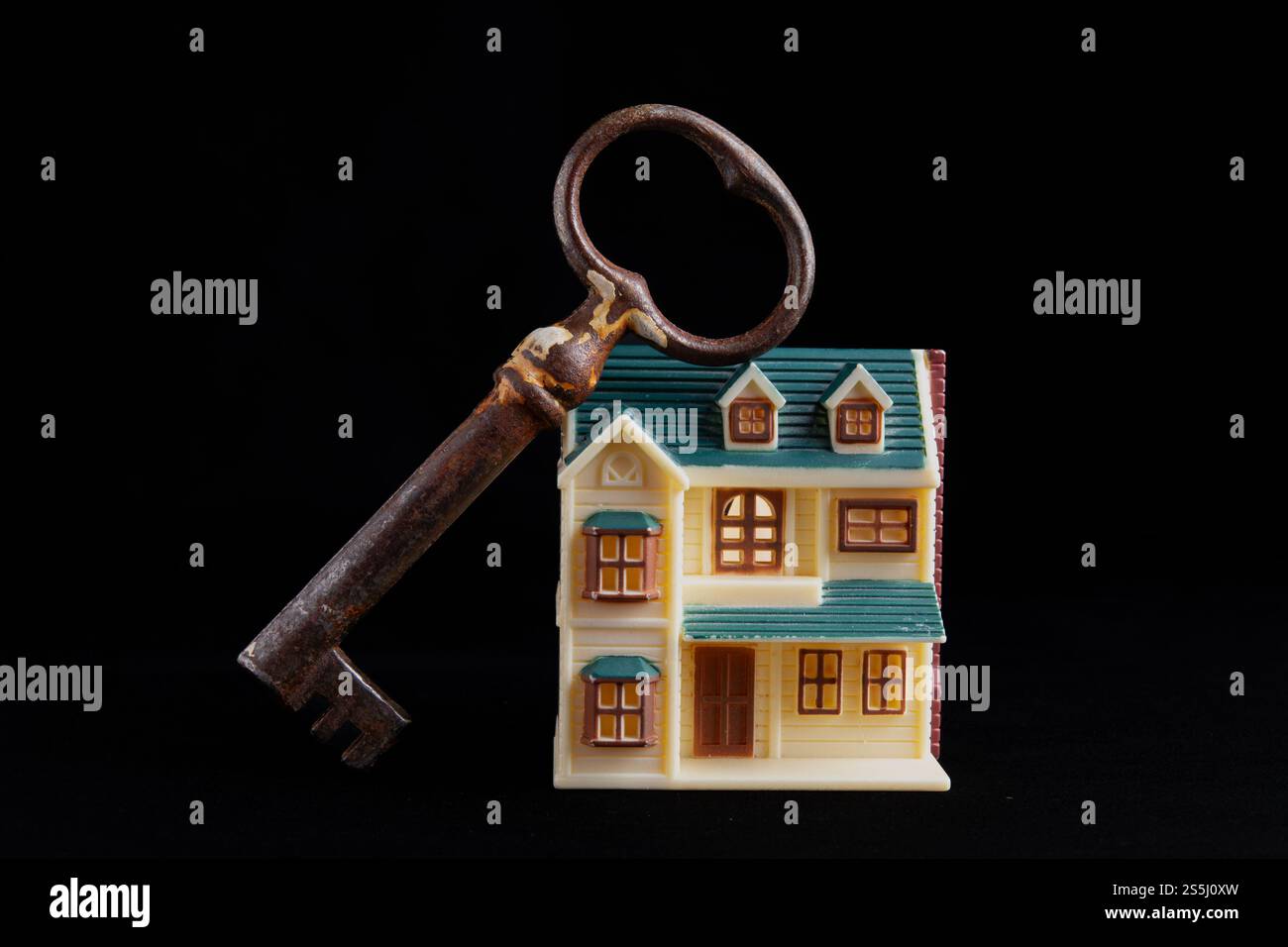 A large vintage key rests beside a detailed miniature house ...