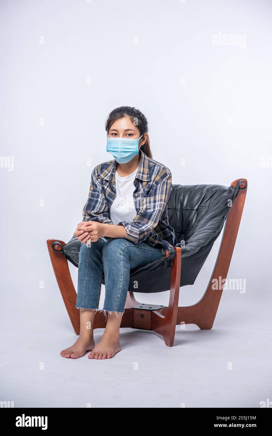 An uncomfortable woman sitting on a chair and wearing a mask Stock ...