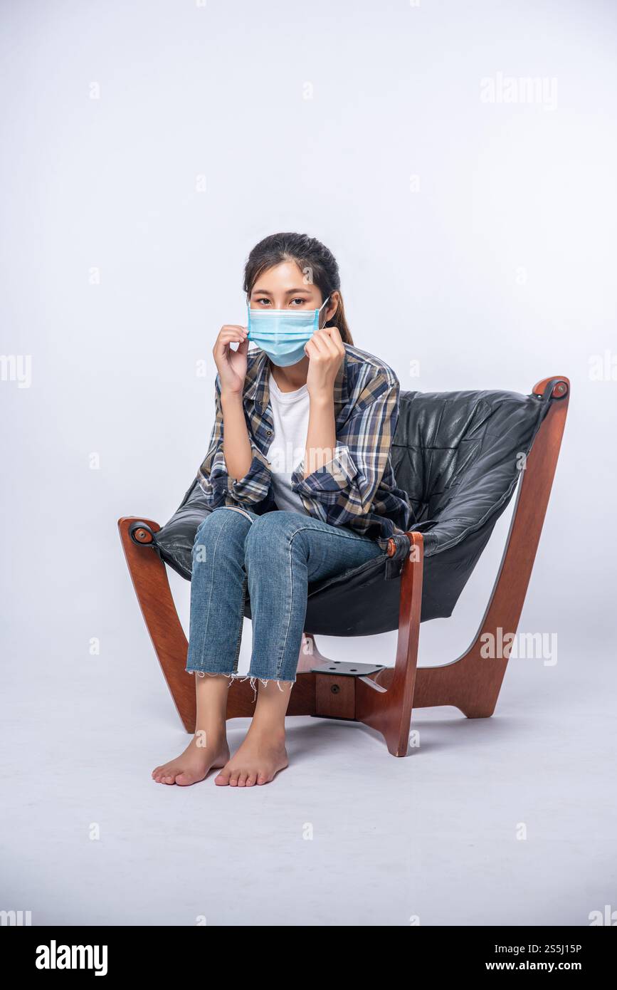An uncomfortable woman sitting on a chair and wearing a mask Stock ...
