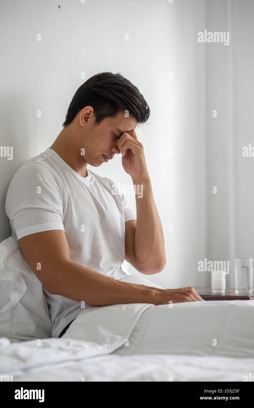 The sick person sat on the bed with his hands and held his nose Stock ...