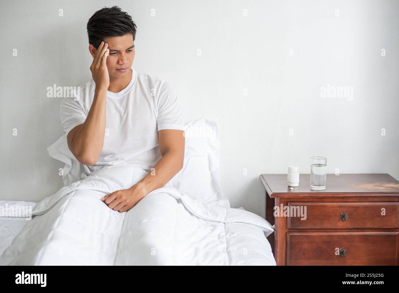 Migraine man, hand touching head, sitting in bed Stock Photo - Alamy