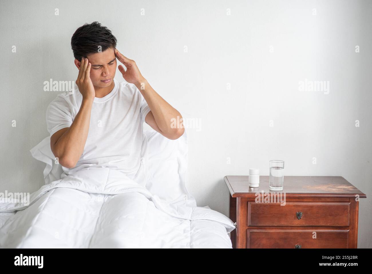 The sick man sat on the bed, touching her head with his hand Stock ...