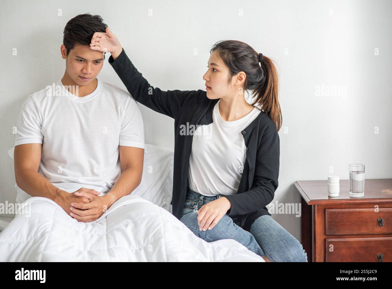 The sick man had a woman look and touch his forehead Stock Photo - Alamy